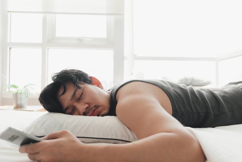 Sleepy Man is Using Smartphone while Lying on the Bed. Stock Image ...