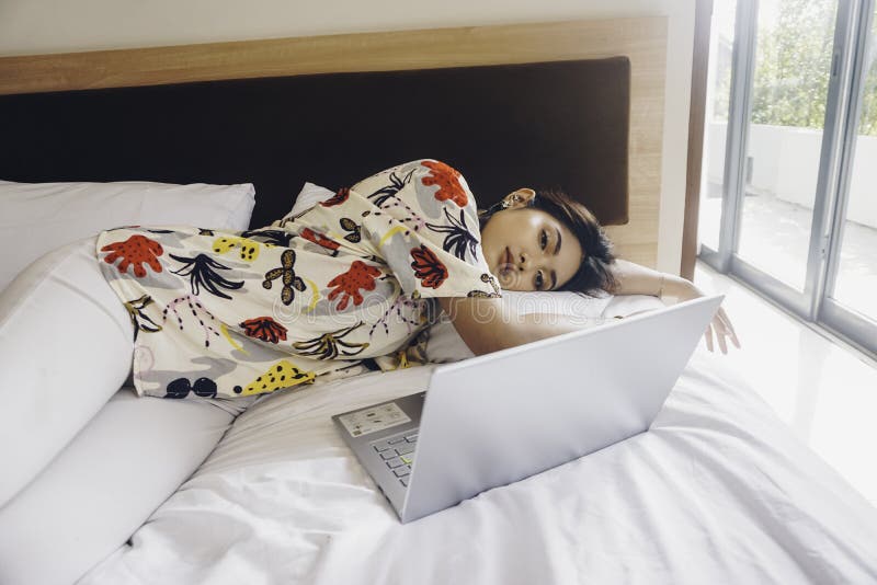 A Sleepy Young Woman Yawning while Working from the Bed Stock Photo ...