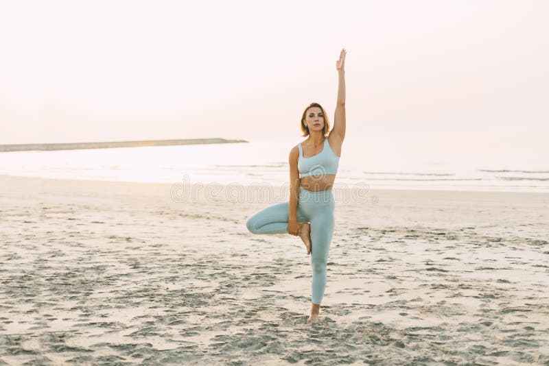 A Slender Girl Practices Yoga on the Beach at Sunset, Performs Asanas ...