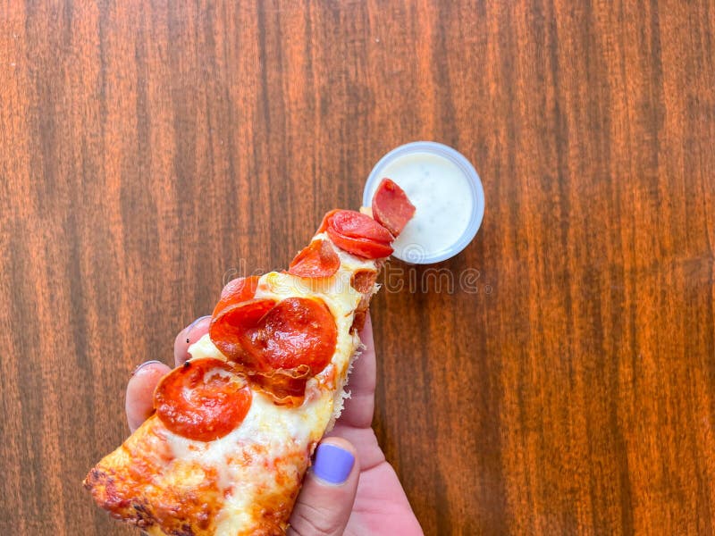 A Slice of Pepperoni Pizza Being Dipped into Ranch Dressing Stock Photo ...