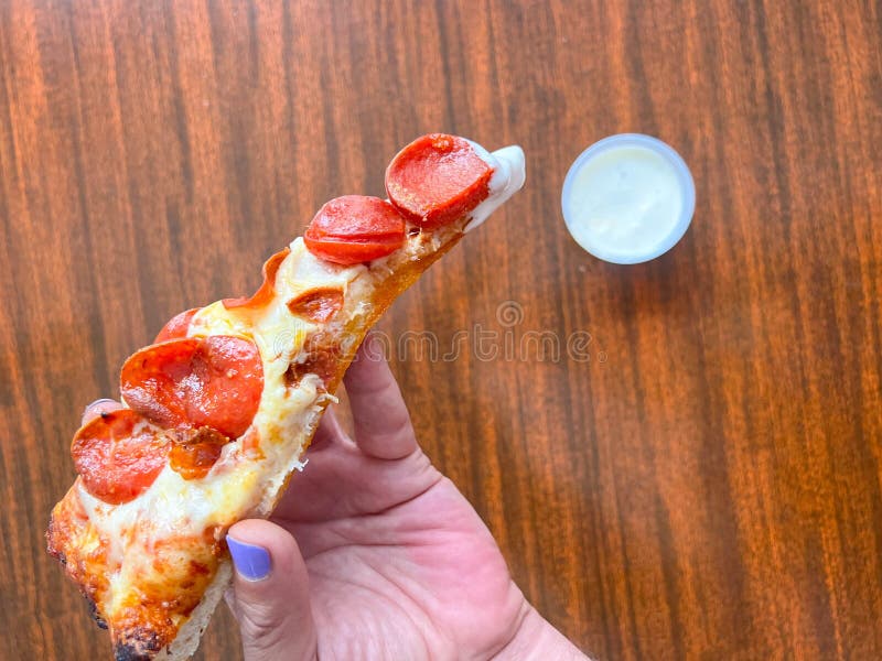 A Slice of Pepperoni Pizza Being Dipped into Ranch Dressing Stock Photo ...