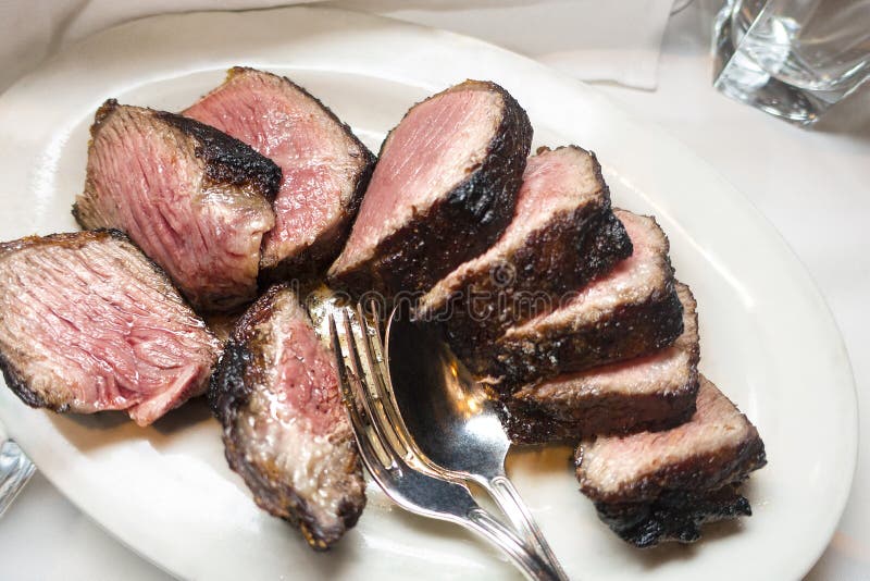 Seared Medium Rare Stake Cut on White Plate with Spoon and Fork Stock ...