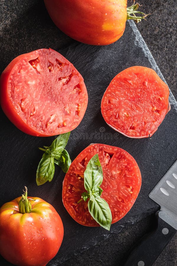 Sliced Bull Heart Tomatoes on Black Table Stock Photo - Image of basil ...