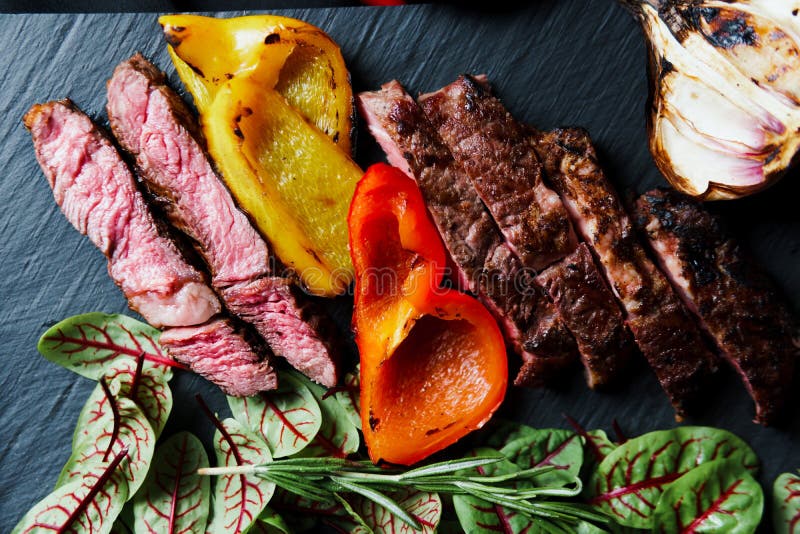 Sliced Grilled Steak Medium Rare Served on Black Cutting Board with ... Sliced Grilled Steak Medium Rare Served on Black Cutting Board with ...