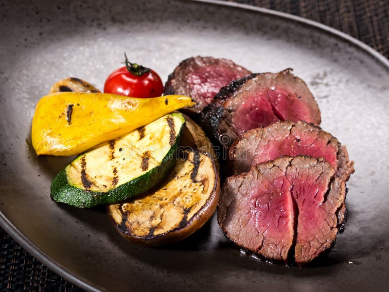 Sliced Medium Rare Filet Mignon Served with Grilled Vegetables on a ...