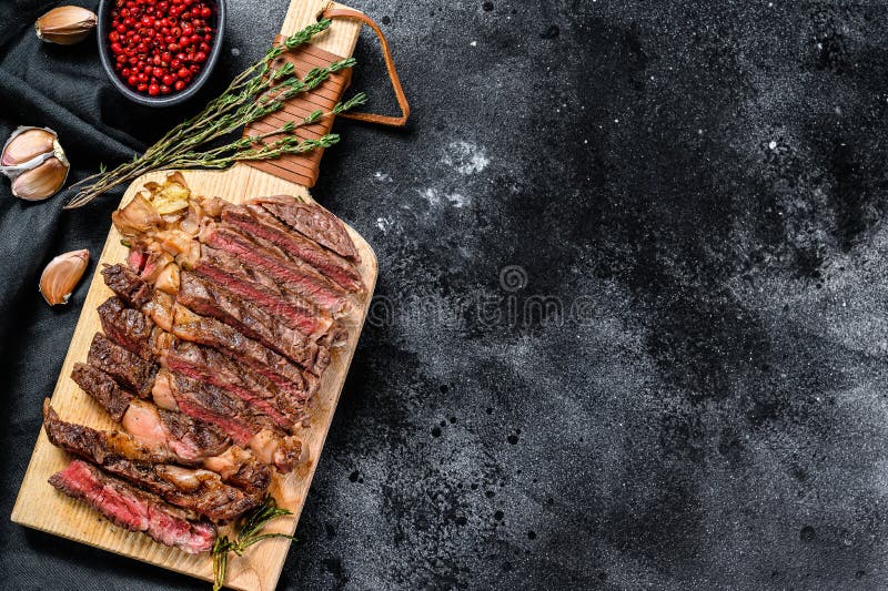 Sliced Rib Eye Steak on a Chopping Board, Medium Rare. Black Background ...