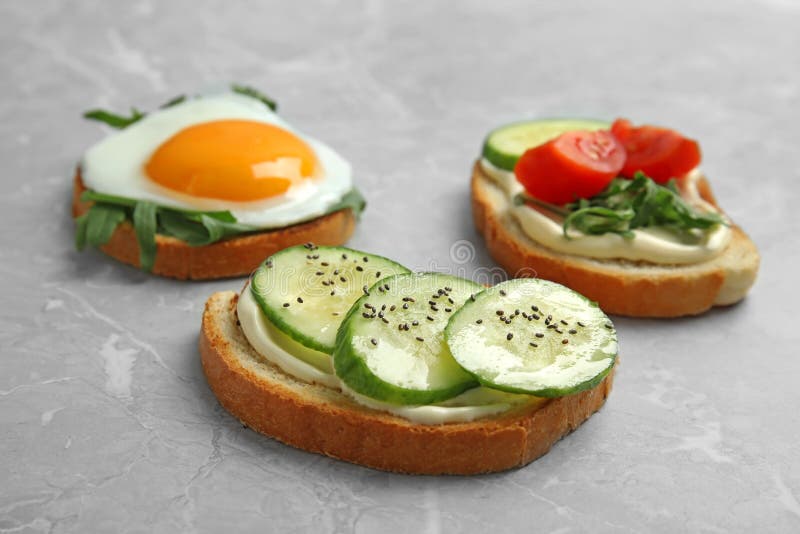 Slices of Bread with Different Toppings on Grey Table Stock Photo ...