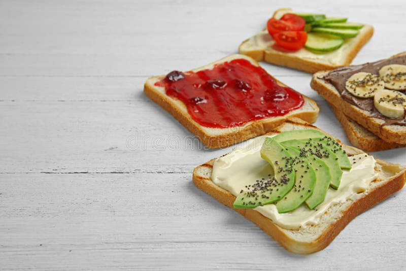 Slices of Bread with Different Toppings on Wooden Table Stock Photo ...