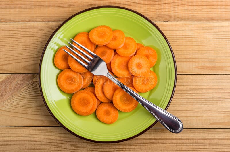 Slices of Raw Carrot in Green Plate and Fork Stock Photo - Image of ...
