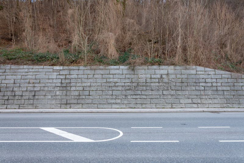 Sloping Stone Wall and Street with White Road Markings Stock Photo ...