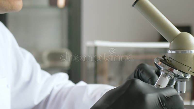 Slow Motion a Man in a White Coat and Glasses Carefully Examines an ...