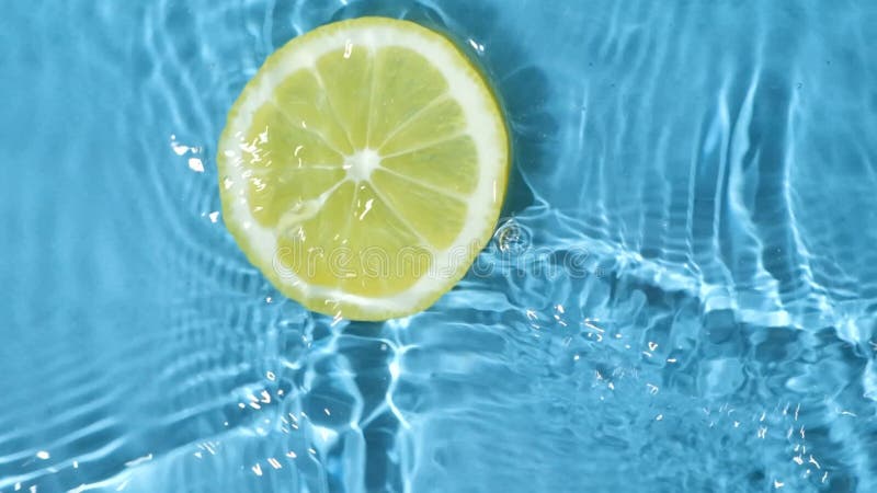 Slow Motion of a Slice of Fresh Lemon Falling into Water Top View ...