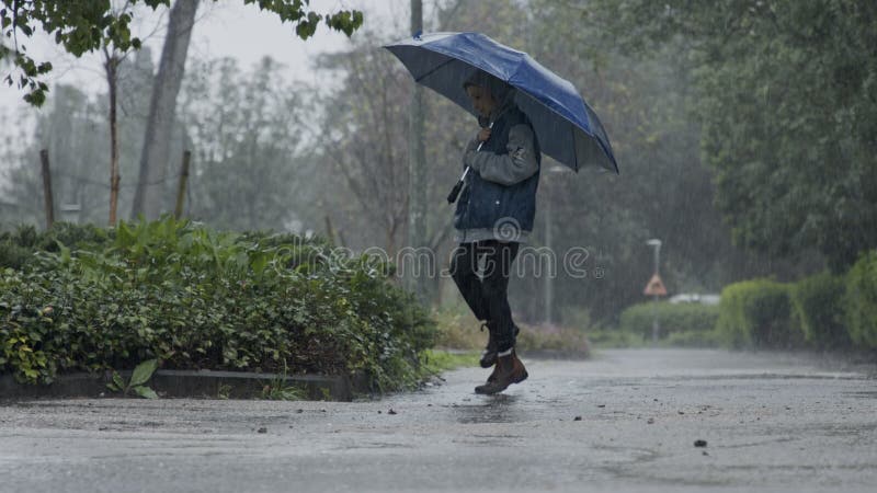 Slow Motion of a Young Boy Jumping in the Pouring Rain Holding an ...