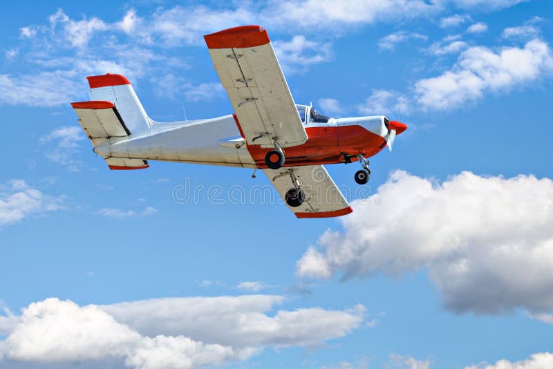A Small Airplane Flying through the Air Under a Cloudy Sky Editorial ...