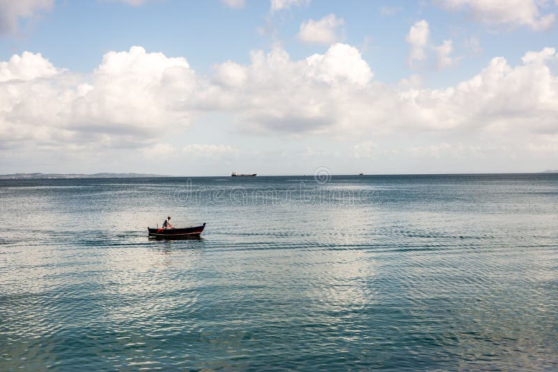 Small Boat Floating in Large Body of Water Near Rocks and Mountains ...
