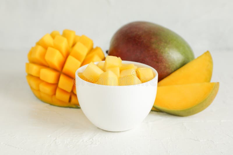 Small Bowl with Mango Pieces and Cut Mangoes on White Background Stock ...