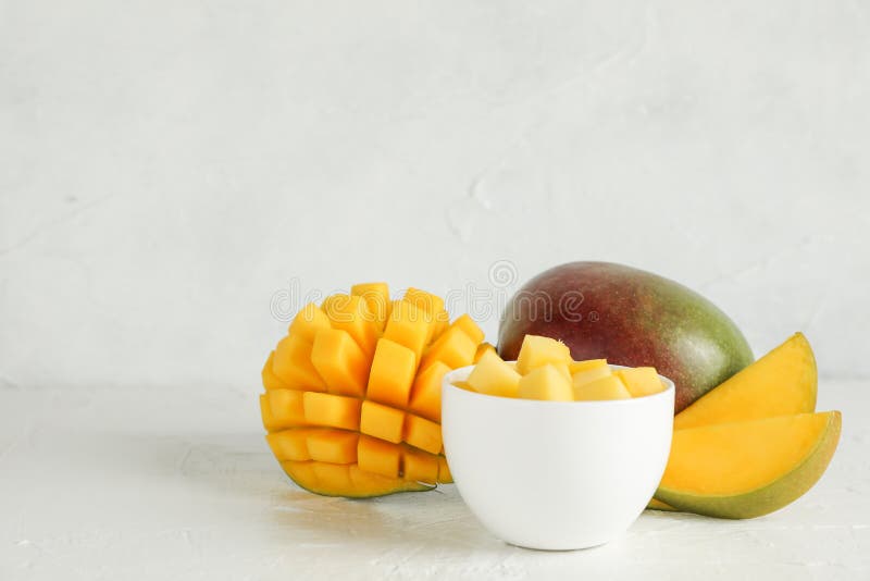 Small Bowl with Mango Pieces and Cut Mangoes on White Background Stock ...