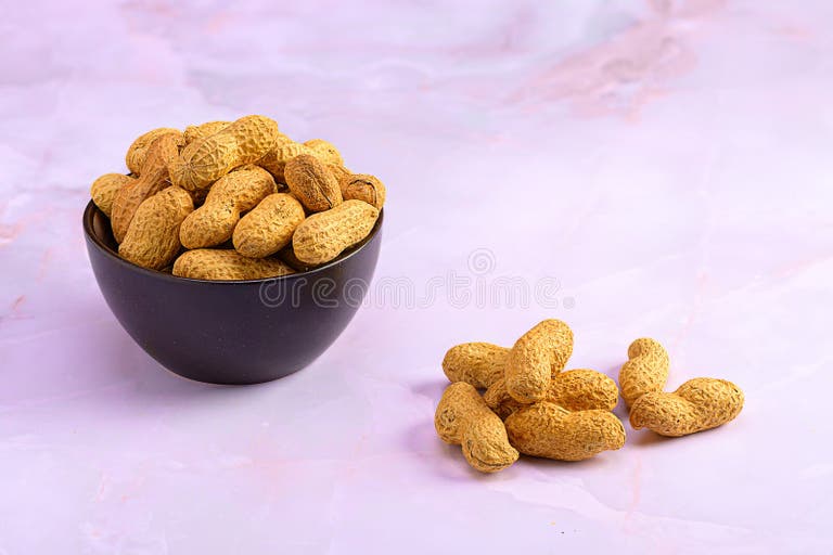 Small Bowl of Peanuts on a Table with Some Peanuts on the Side Stock ...