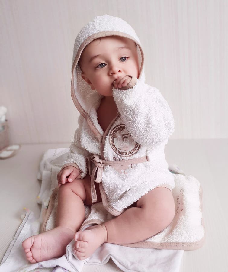 A Small Boy with Blond Hair and Eyes in a Bathrobe is Sitting on a ...