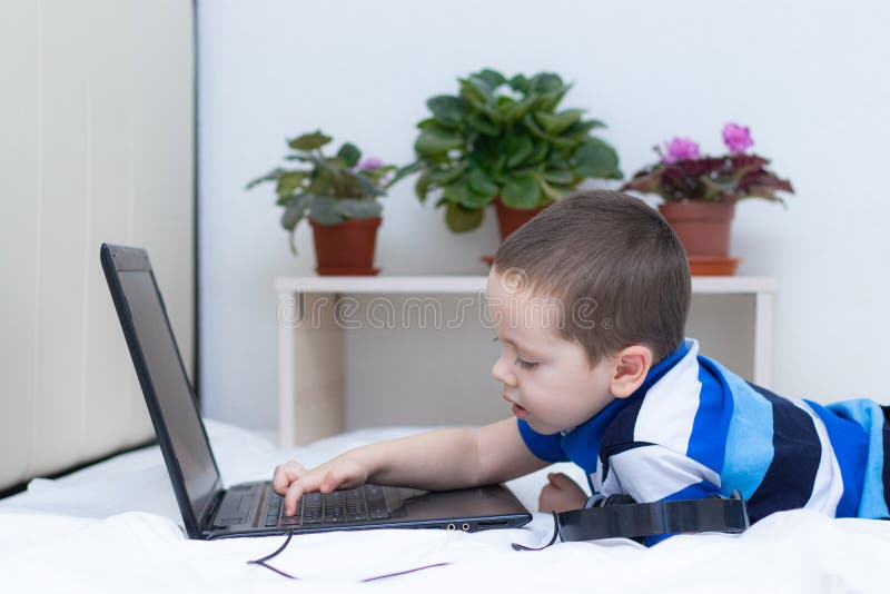 A Small Boy with a Laptop on the Bed. Remote Learning . Health Safety ...
