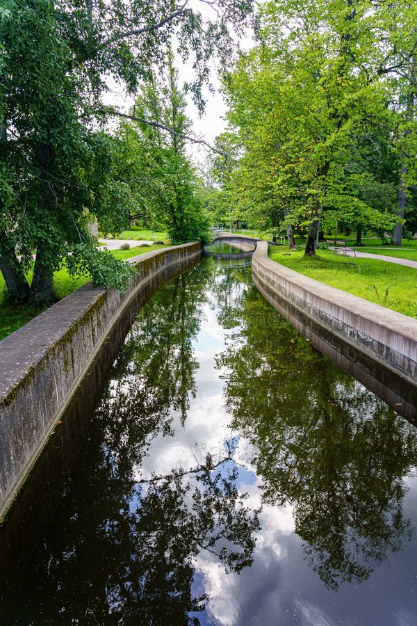 Small Bridge Over Quiet Water Channel in the Park Next To Large Trees ...