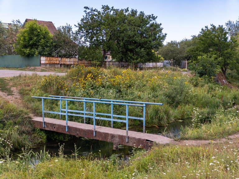 A Small Bridge Over a Small Stream in a Grassy Field Stock Image ...