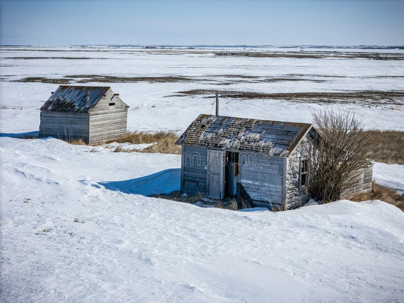 Small Cabin is in the Snow with a Large Empty Field in the Background ...