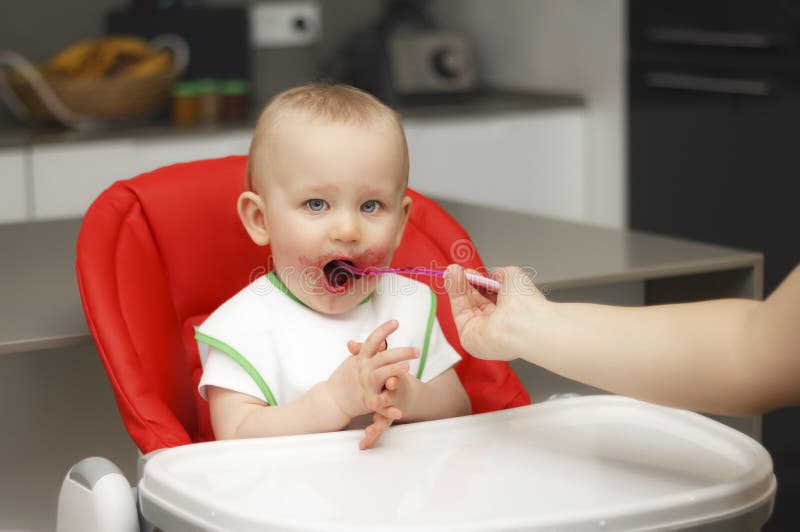A Small Child Eats Jam and Cereal, Sits on a Highchair Stock Image ...
