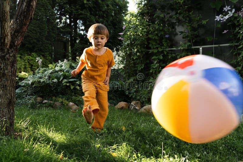 Small Child Playing with Beach Ball in Backyard. Stock Photo - Image of ...