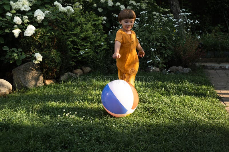 Small Child Playing with Beach Ball in Backyard. Stock Photo - Image of ...