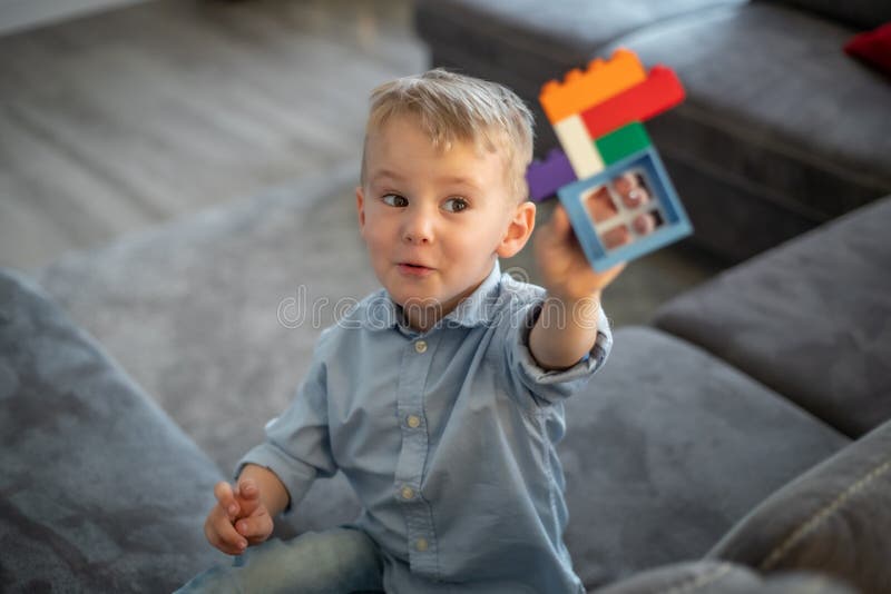 A Small Child Plays with Blocks. the Boy Sits on the Sofa and Builds a ...