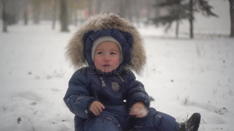 A Small Child Sits in the Snow in the Park and Cries from the Cold. the ...