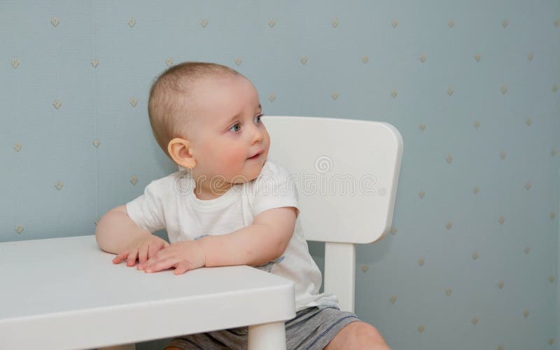 A Small Child Sits at a Table and Looks Away Stock Photo - Image of ...