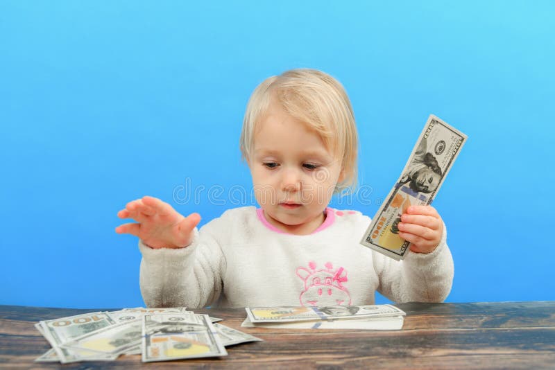 A Small Child is Sorting Out Dollars on the Table and Looking at Them ...