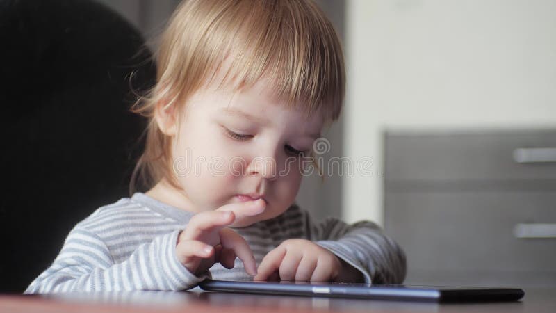 A Small Child of 2-3 Years Old Sitting on a Chair at the Table, Looking ...