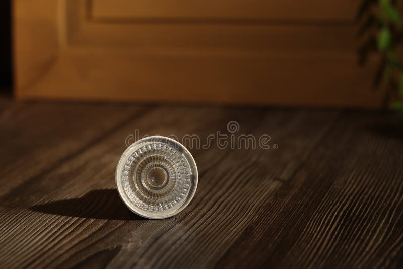 A Small, Clear, White Light Light Bulb Lying on a Brown Wood Texture ...