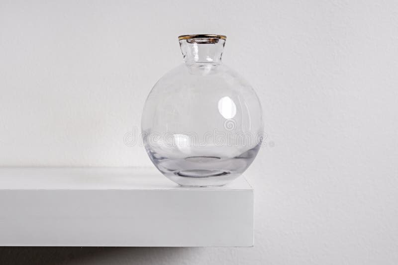 A Small Decorative Clear Glass Jar on a Plain White Wooden Shelf Stock ...