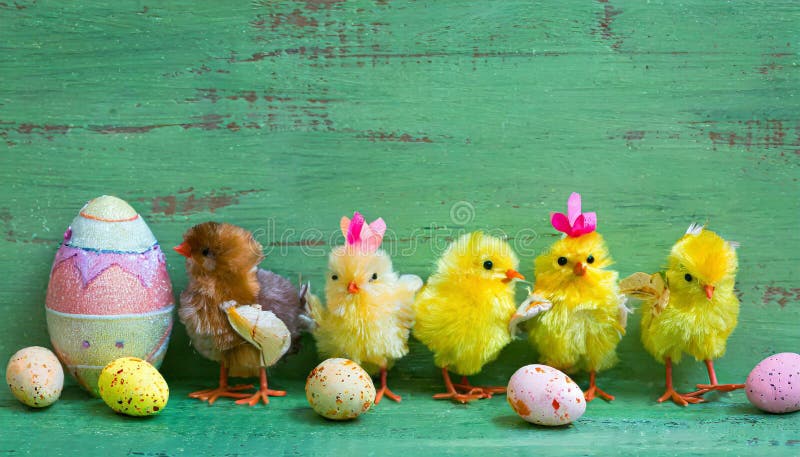 Small Decorative Easter Chickens and Eggs in a Row on Green Background ...