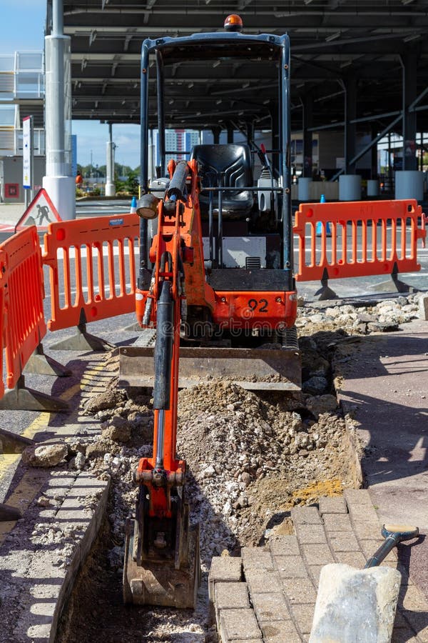 A Small Digger Digging Up the Pavement during Ground Works Editorial ...