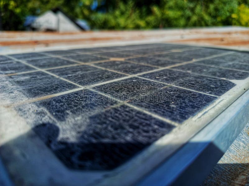A Small, Dirty Solar Panel Sits on a Rusty Corrugated Metal Roof Under ...