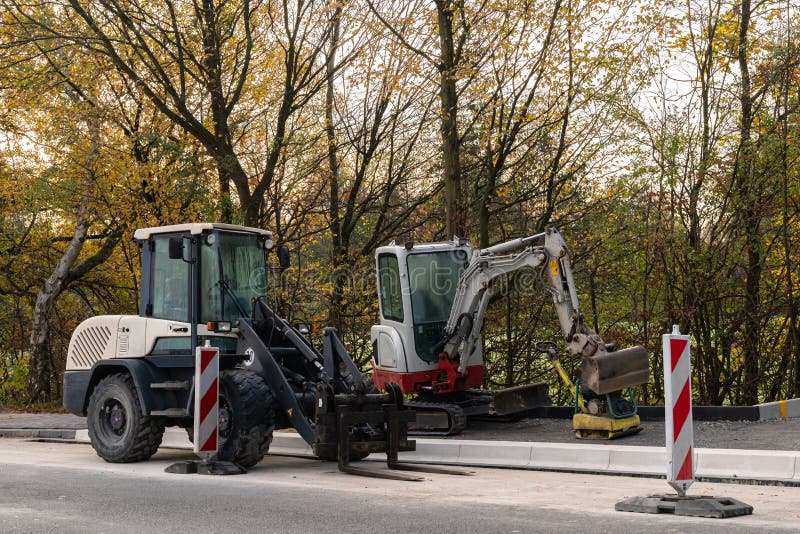 Small Excavator and Forklift Stand on the Side of the Road. Stock Photo ...