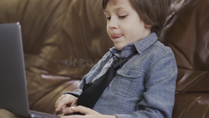 Small Excited Boy Working on a Laptop Computer on the Leather Sofa ...