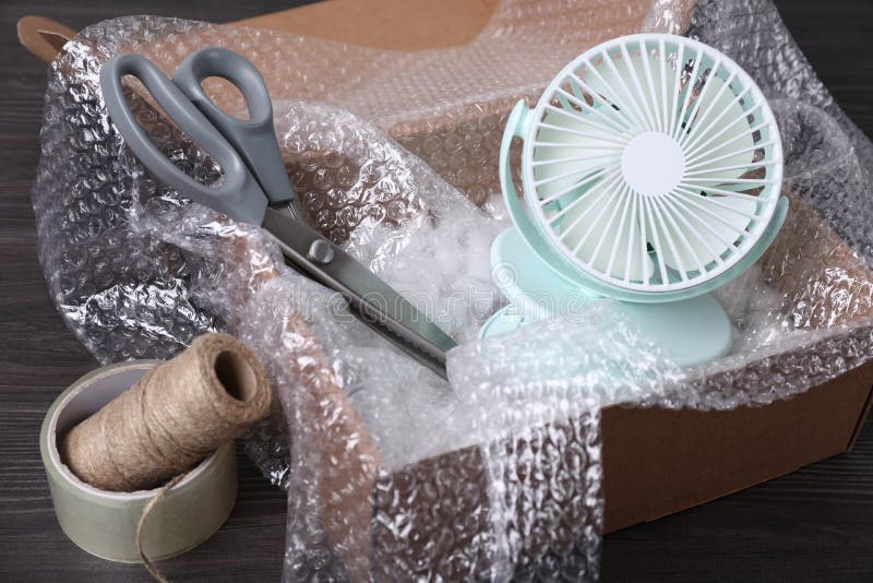 Small Fan with Bubble Wrap in Cardboard Box and Packaging Items on Dark ...
