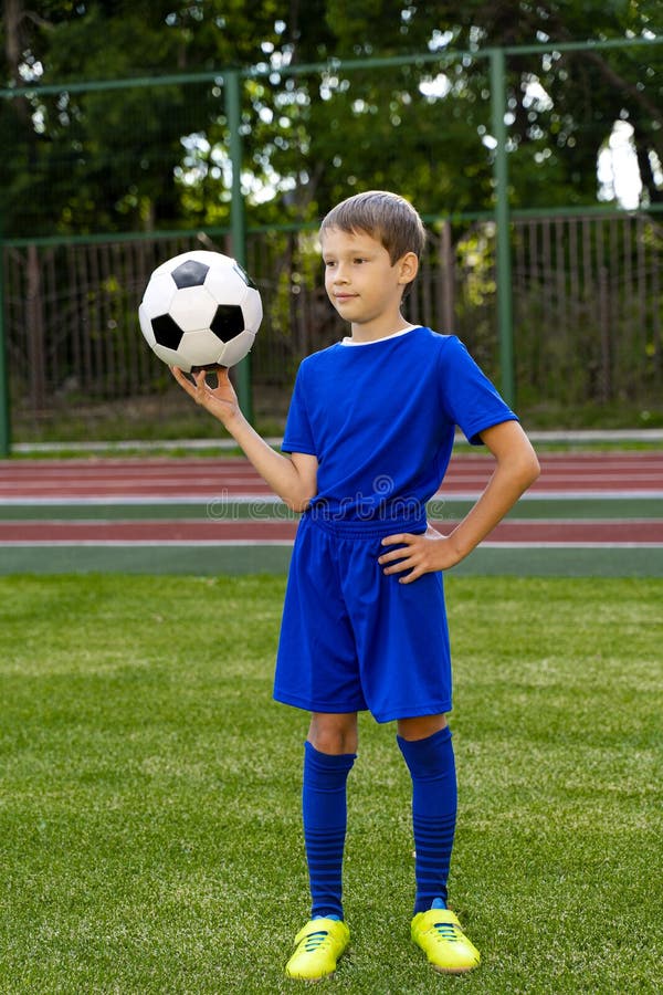 A Small Football Player with a Ball Stands on a Green Football Field in ...
