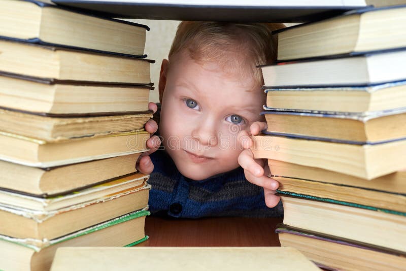 A Small Funny Boy Looks Out from a Stack of Books Stock Image - Image ...