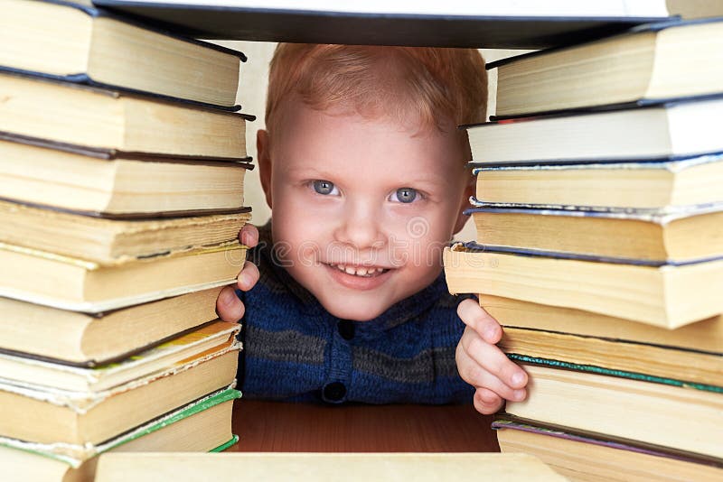 A Small Funny Boy Looks Out from a Stack of Books Stock Image - Image ...