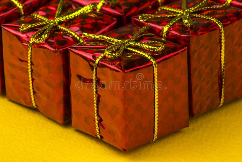 Small Gifts Packed in Red Shiny Paper. Red Gift Boxes Closeup on Yellow ...