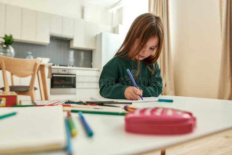 A Small Girl Writing Notes Sitting Alone at a Table in a Big Bright ...