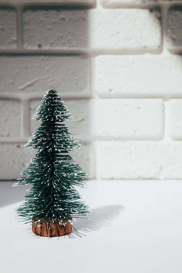 Small Green Decorative Christmas Tree with Shadows on a White Brick ...