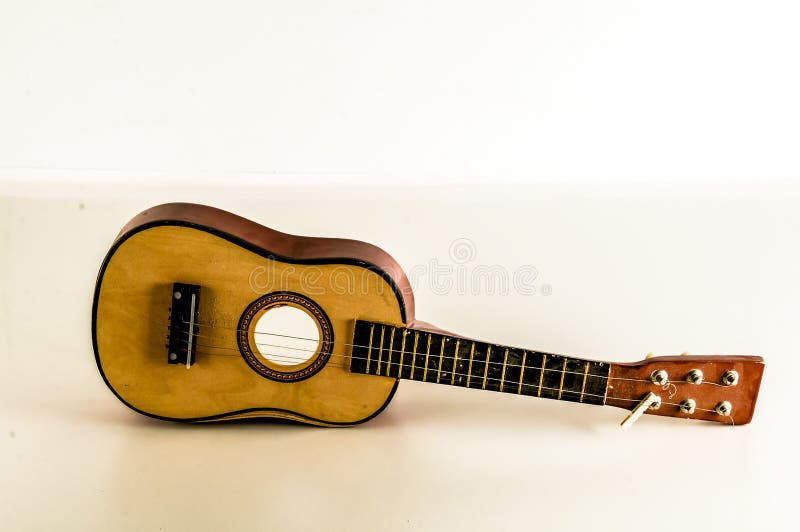 A Small Guitar is Sitting on a White Table Stock Photo - Image of ...